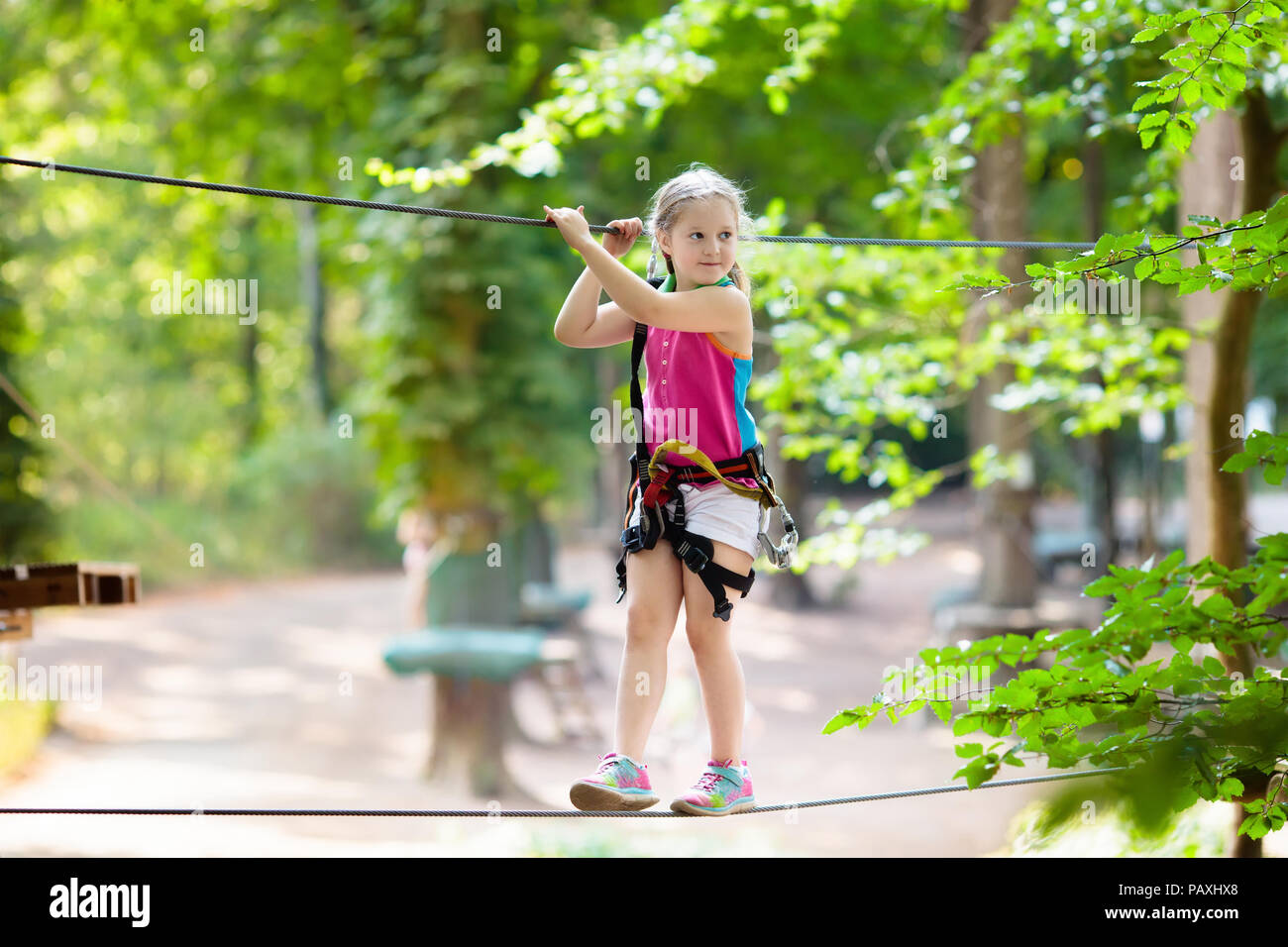 Child in forest adventure park. Kids climb on high rope trail. Agility ...