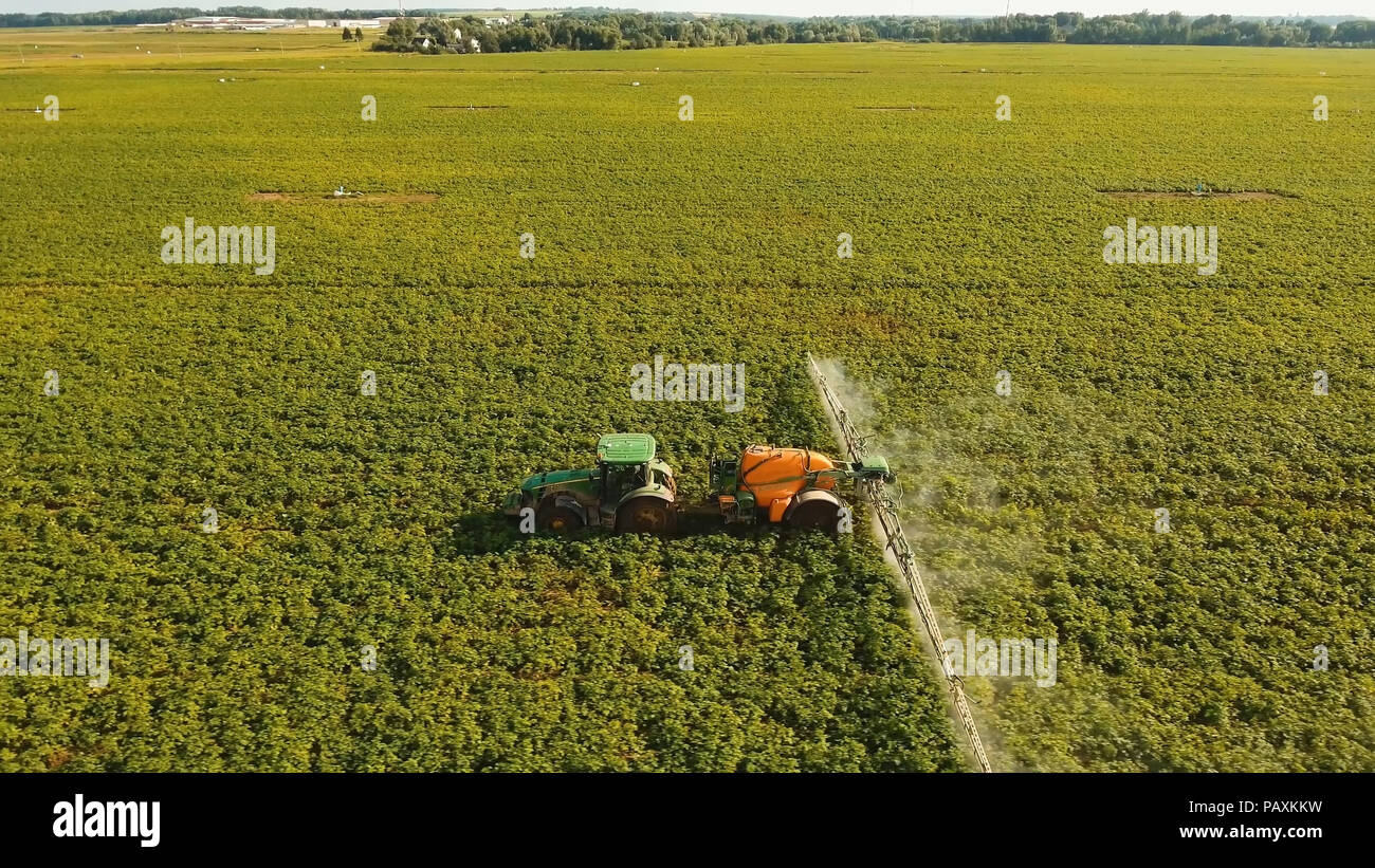 Aerial view tractor spraying the chemicals on the large green field ...