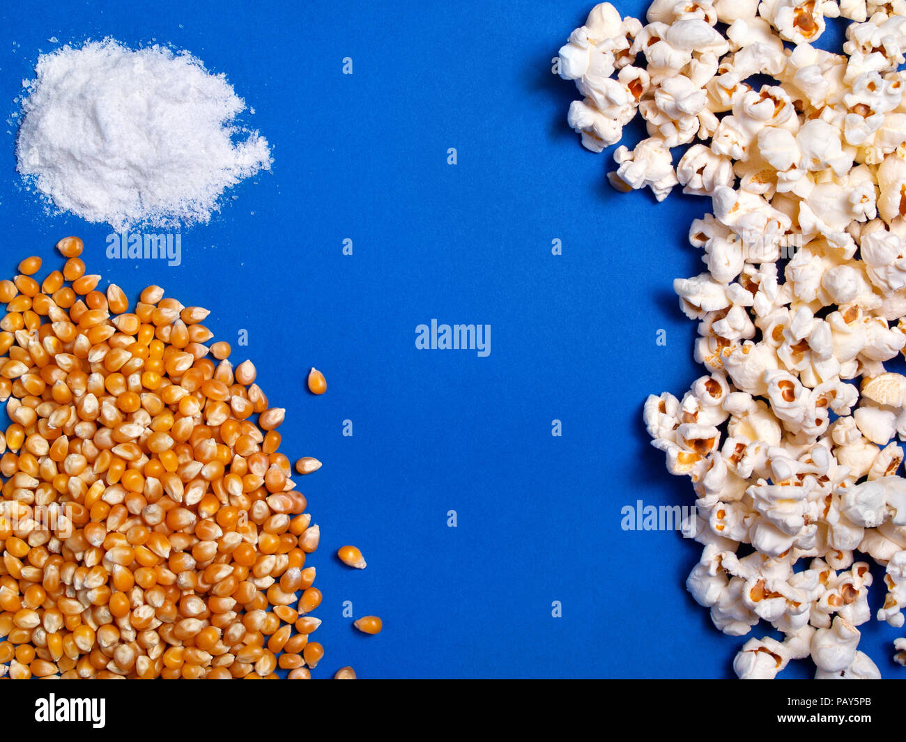 Popcorn, corn kernels, salt lie on a blue background close-up view from ...