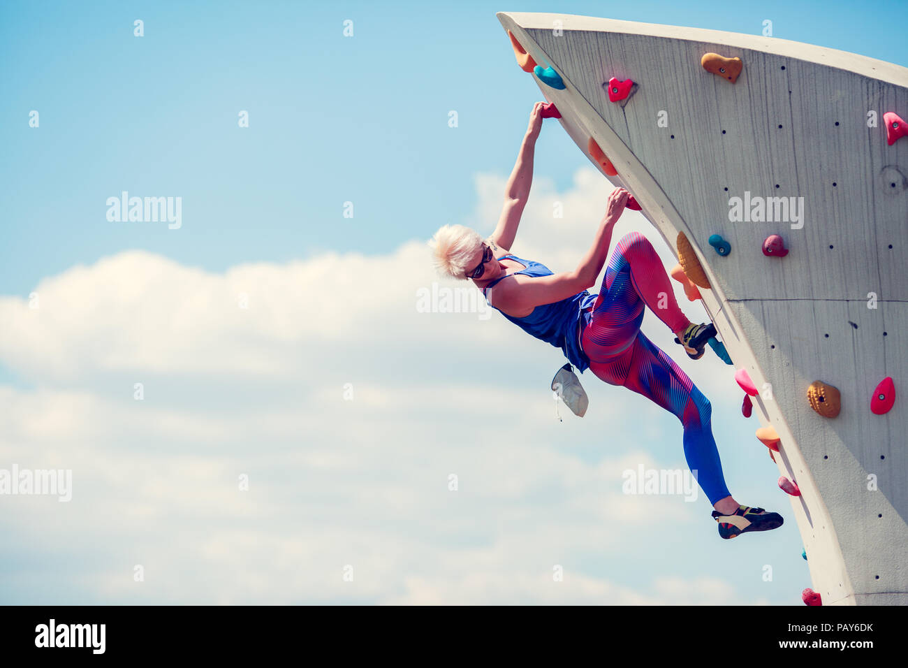 Image of young sportive woman clambering on rocky summer day against ...