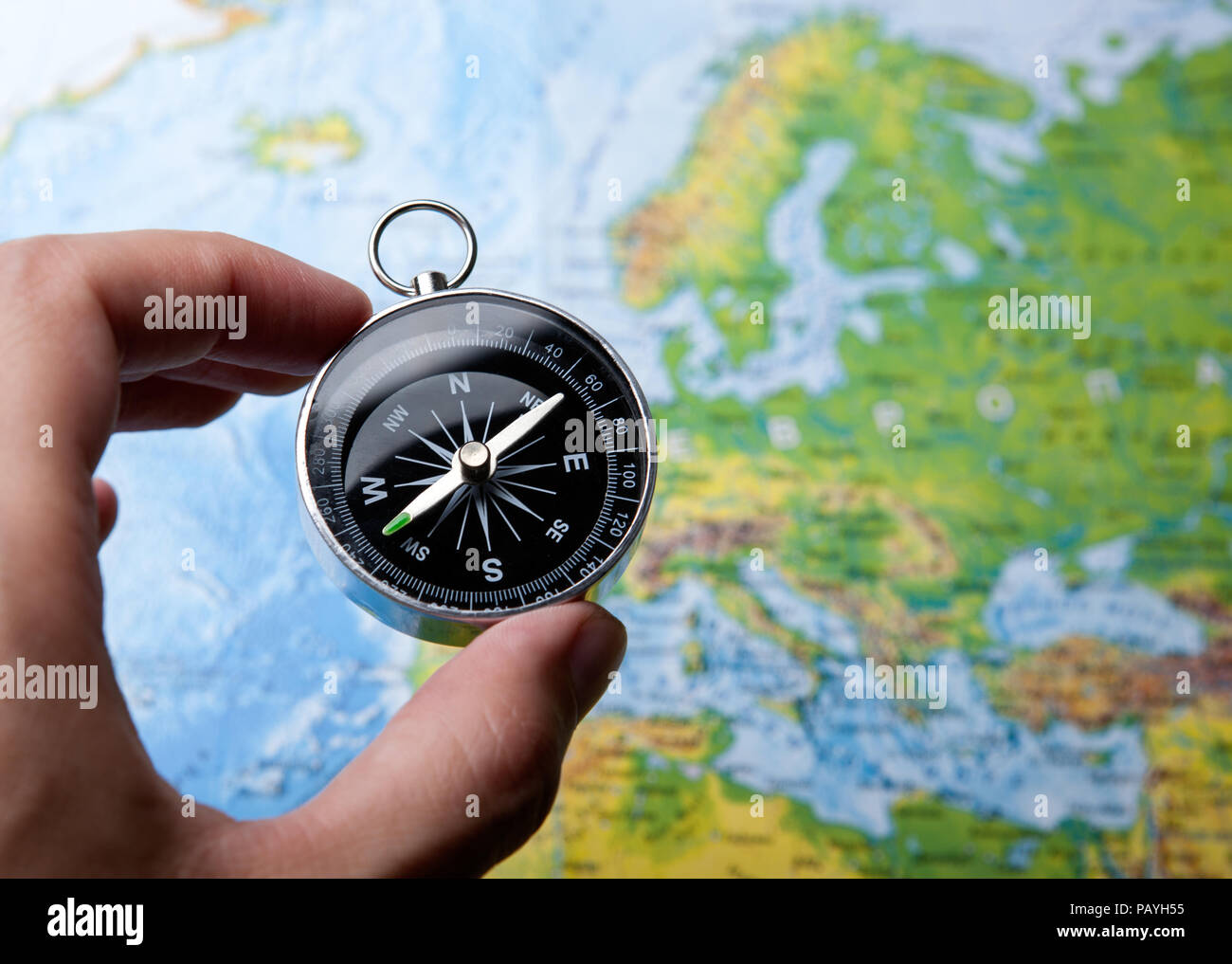 compass in the hand on the background of a map of the world closeup ...