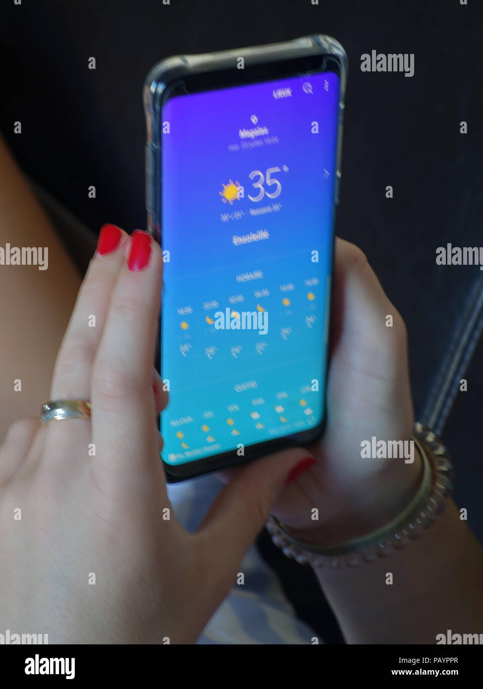 Girls hand holding mobile showing local heatwave temperature now Stock ...