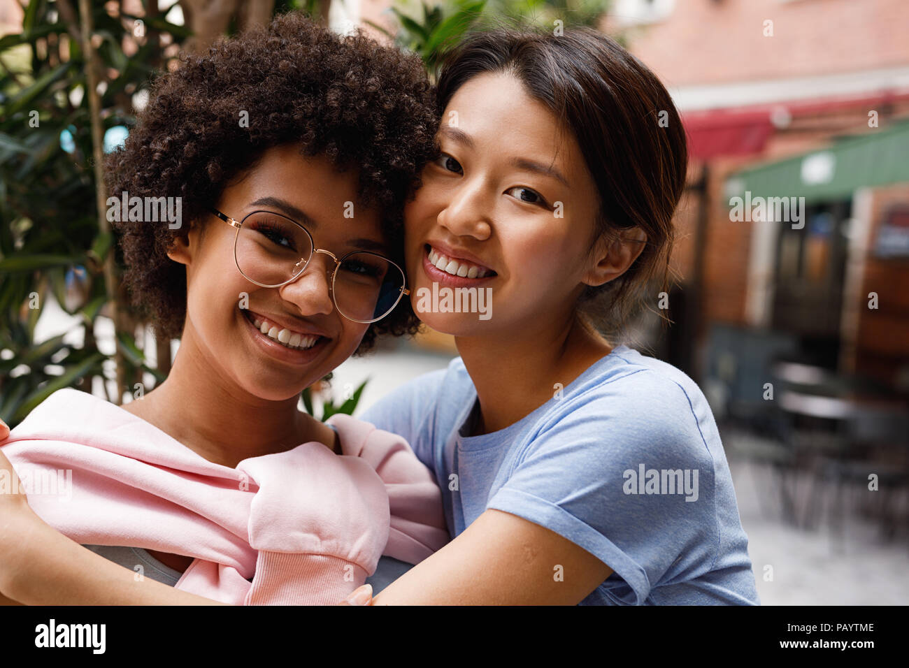Two smiling friends looking at a camera, standing outdoors Stock Photo ...