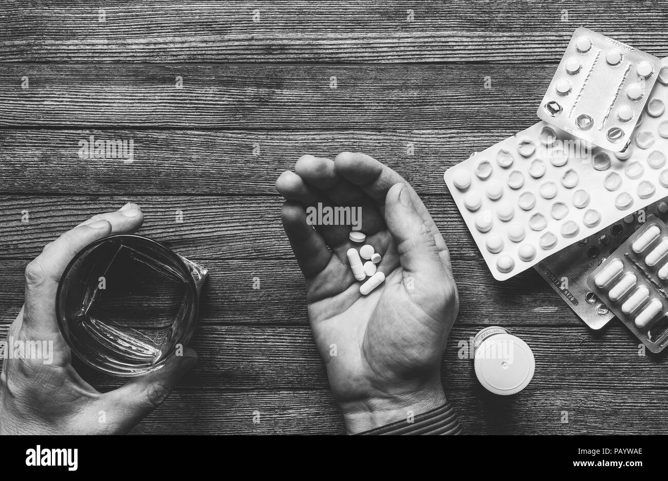 man is going to eat pills and capsules and drink water, black and white ...