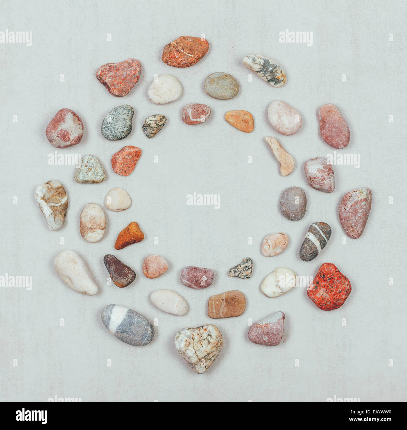 frame circle of multi-colored sea and river stones on grey background ...