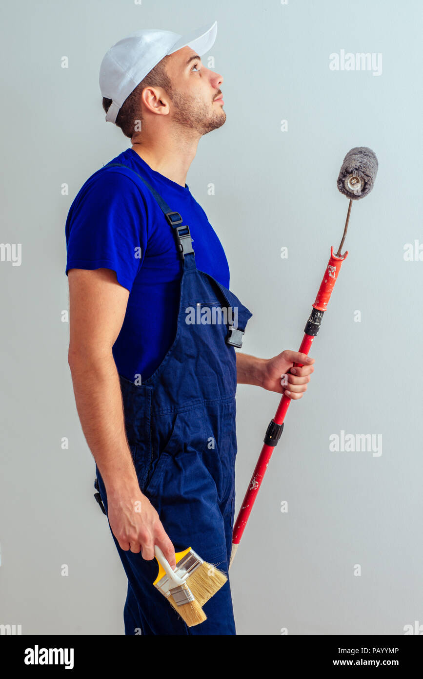 Man on white background holds paint stick roller and brushesh for ...