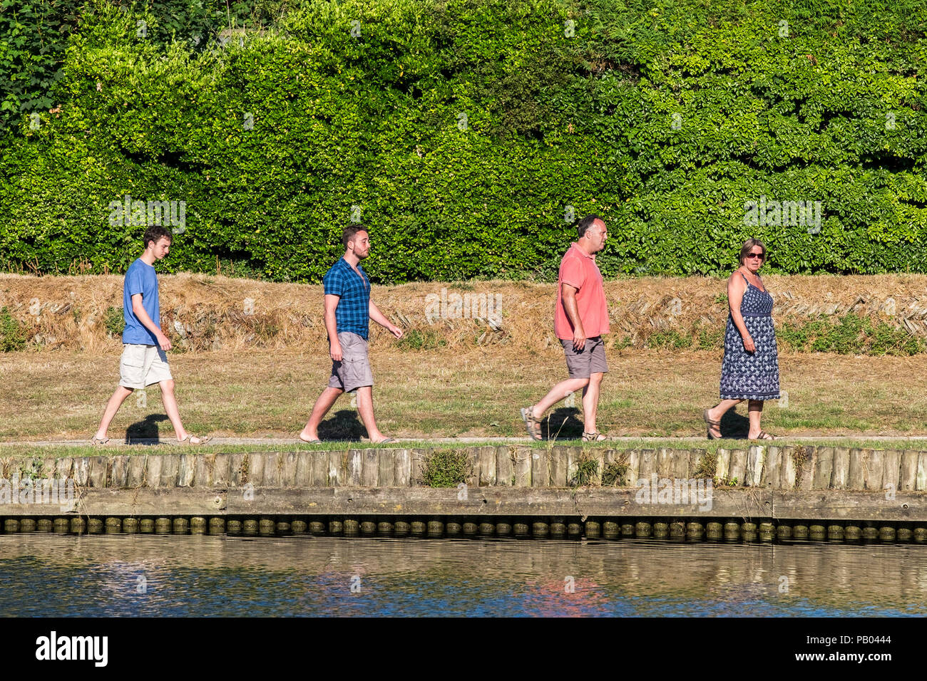 A family walking in single file on the banks of a lake Stock Photo - Alamy