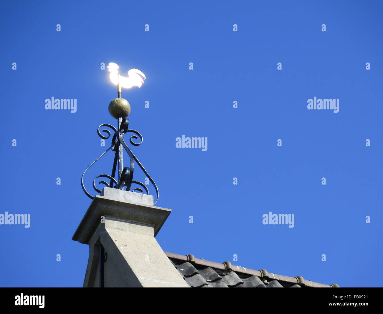 Sun reflecting on gold painted cockerel shaped weather vane in Dutch ...