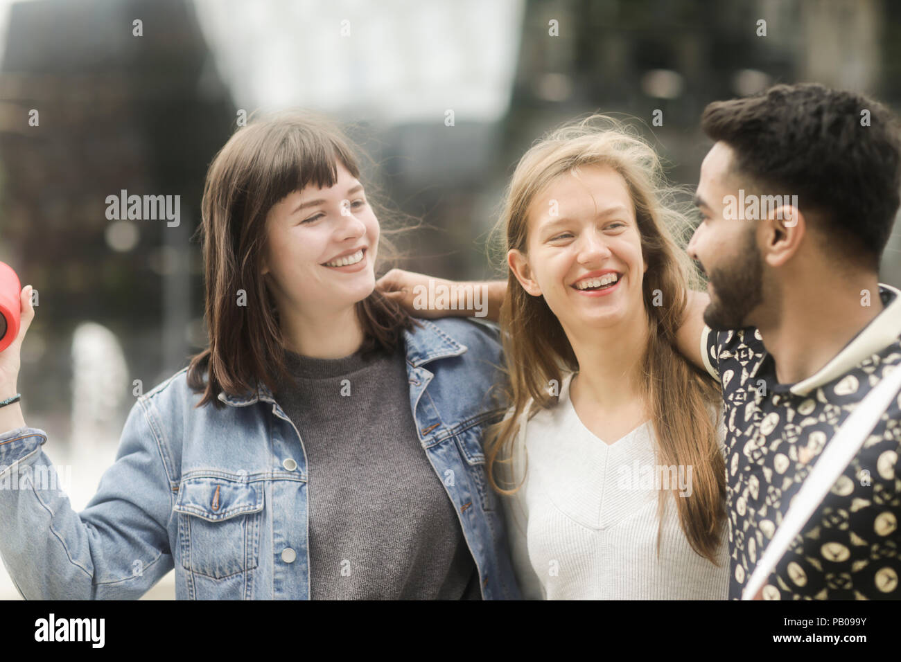 Three friends with their arms around each other listening to music ...