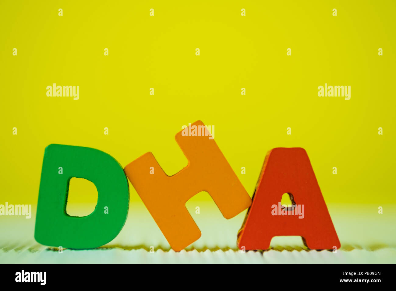 DHA text alphabet on white wooden table. yellow wall background with ...