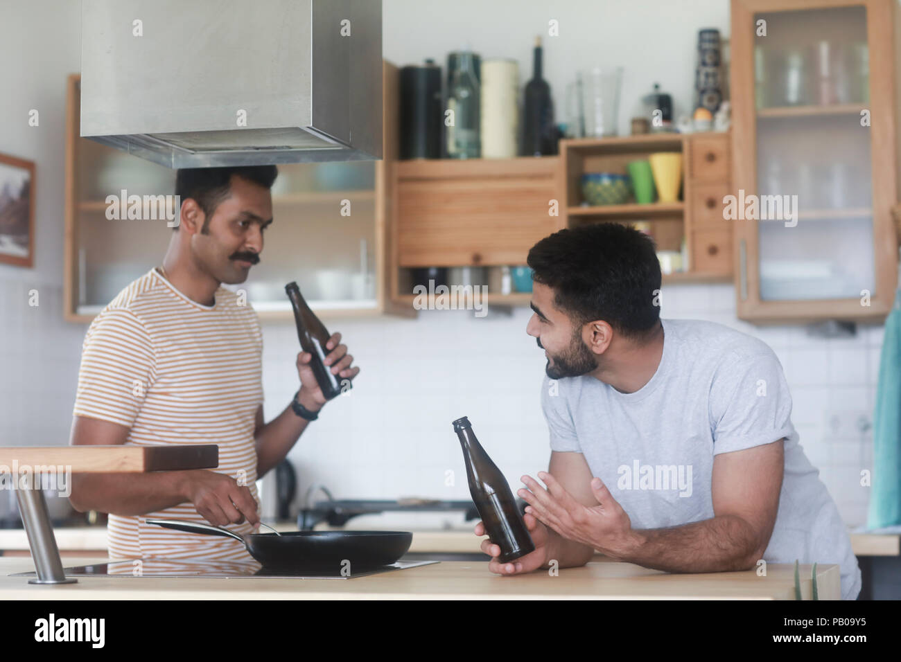 Two men drinking beer while cooking dinner Stock Photo - Alamy