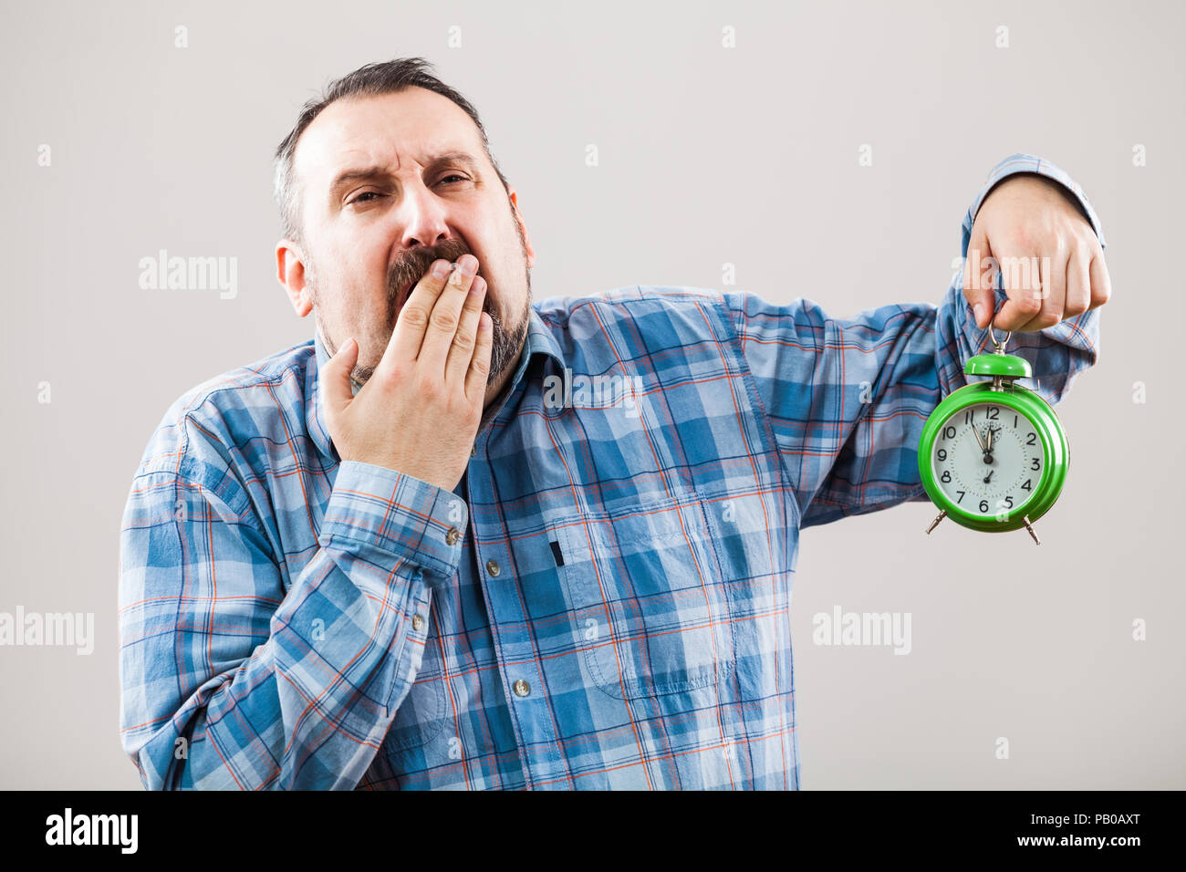 Studio shot portrait of tired man who is holding clock Stock Photo - Alamy
