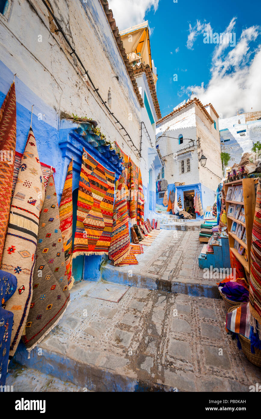 Narrow alley, carpet and craft shop, blue houses, medina of Chefchaouen ...