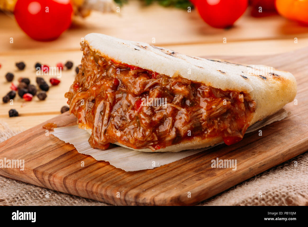 Arepa with seasoned mashed meat and some ingredients of its preparation ...