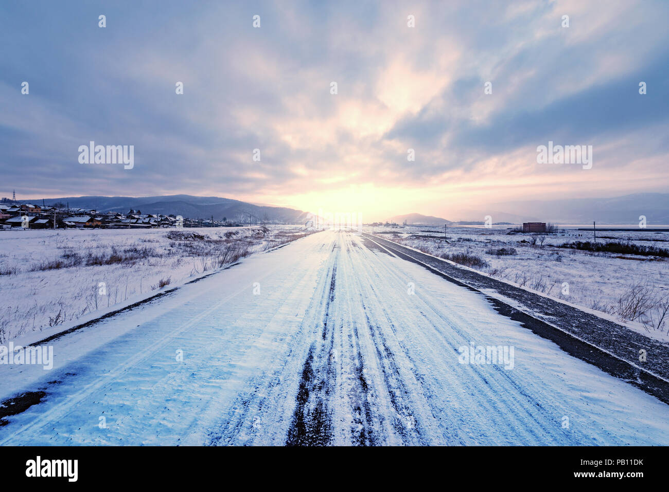 Highway to the small settlement at cold winter sunset time Stock Photo ...