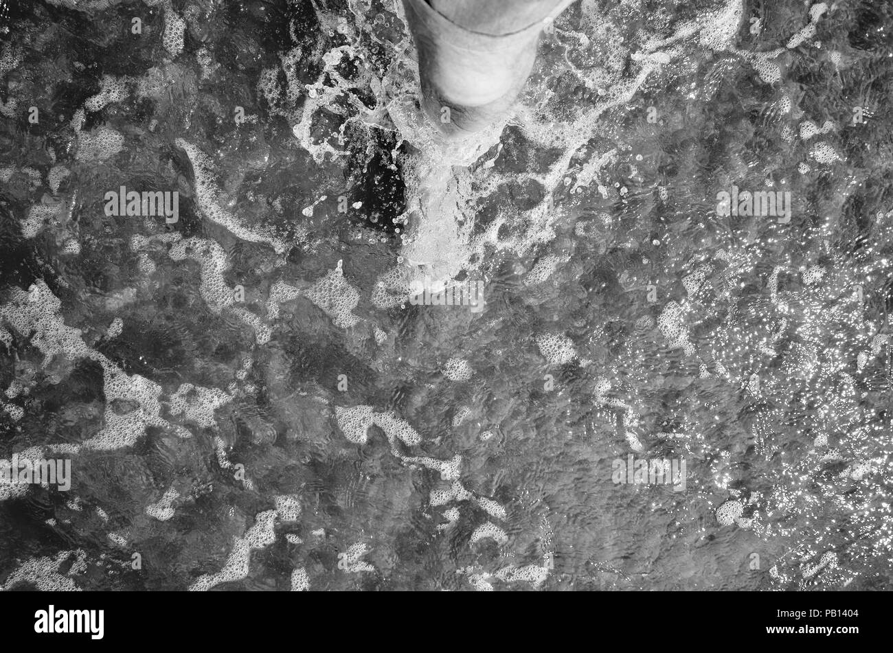 Monochrome. Male bare foot splashing through seawater on sea's edge ...