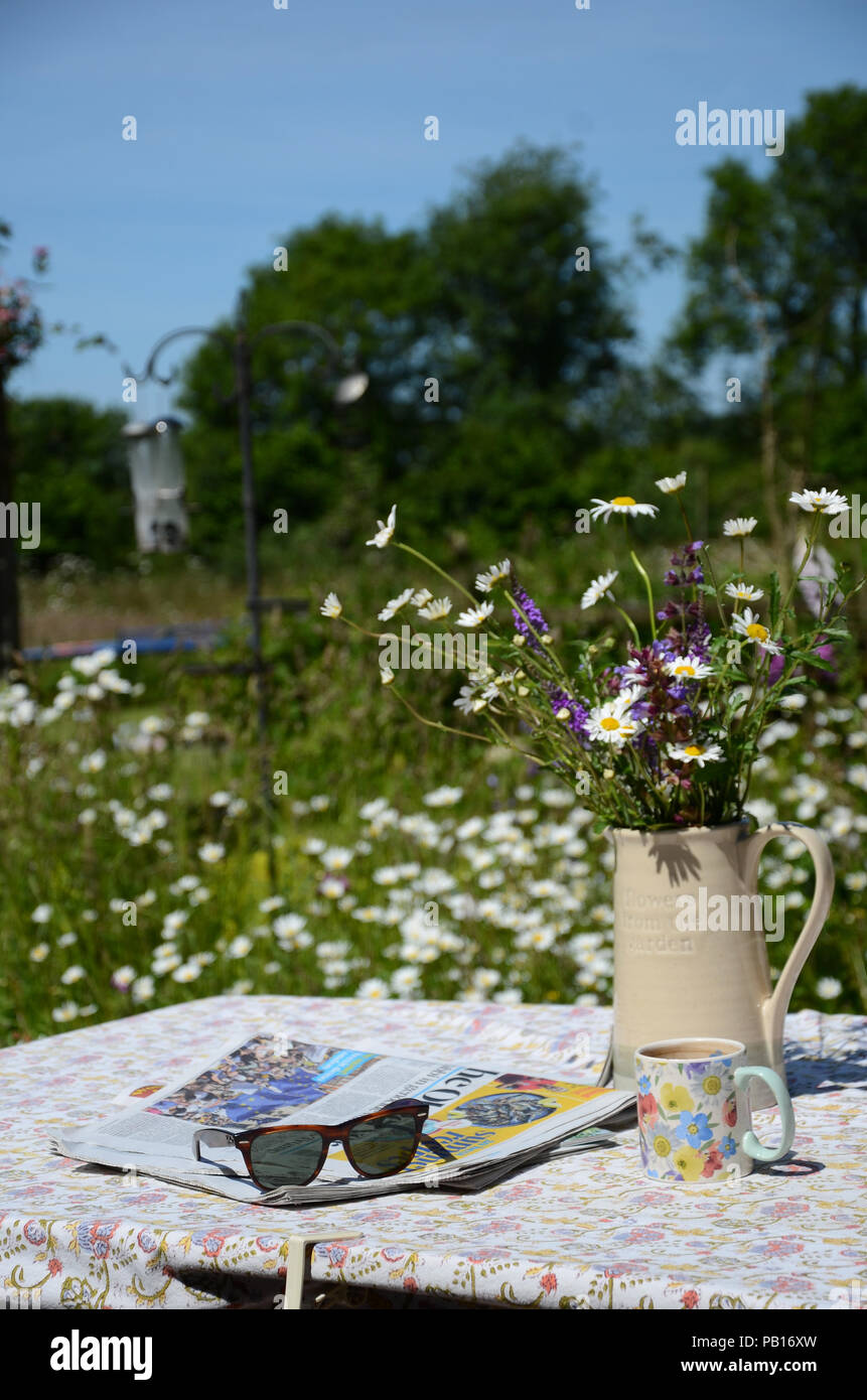 Coffee or tea break in a sunny back garden table with the Sunday papers ...
