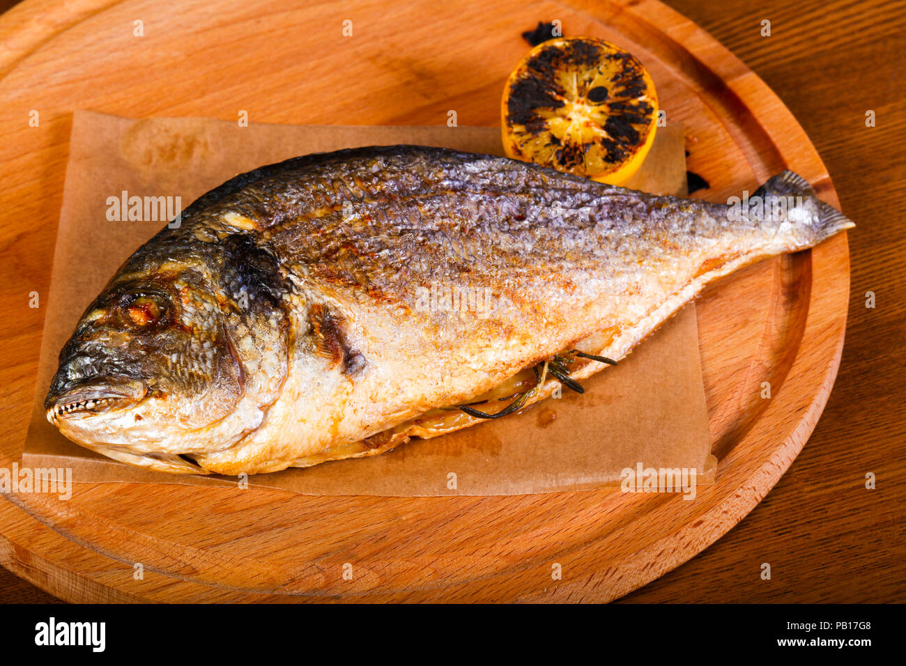 Grilled dorada with lemon over wooden background Stock Photo - Alamy