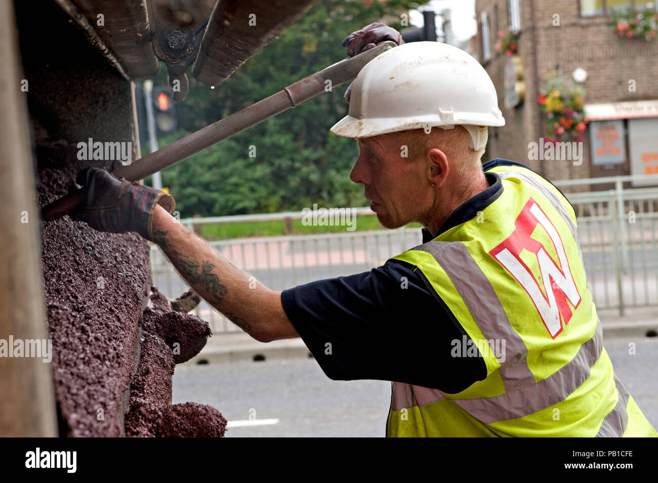 Inspecting red asphalt as it pours from a lorry in the UK Stock Photo ...