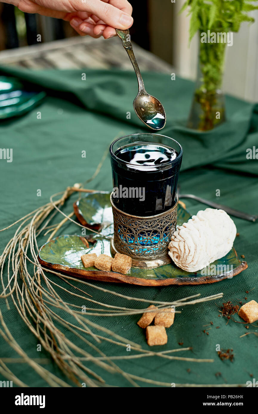 Tea in a Cup holder, hand mixing tea spoon Stock Photo - Alamy