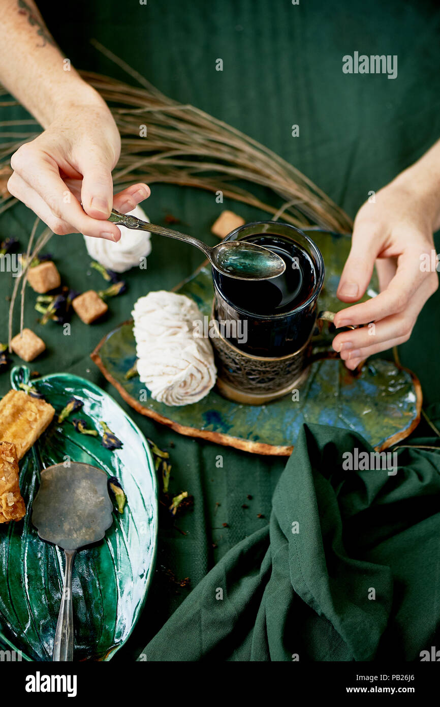 Tea in a Cup holder, hand mixing tea spoon Stock Photo - Alamy