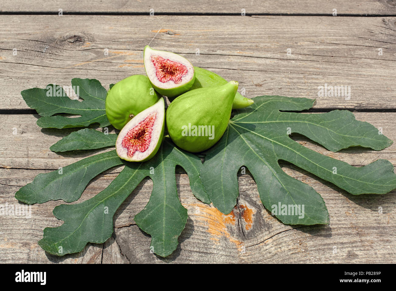 halved fig on figs and fig leafs,wood board as background, copy space ...