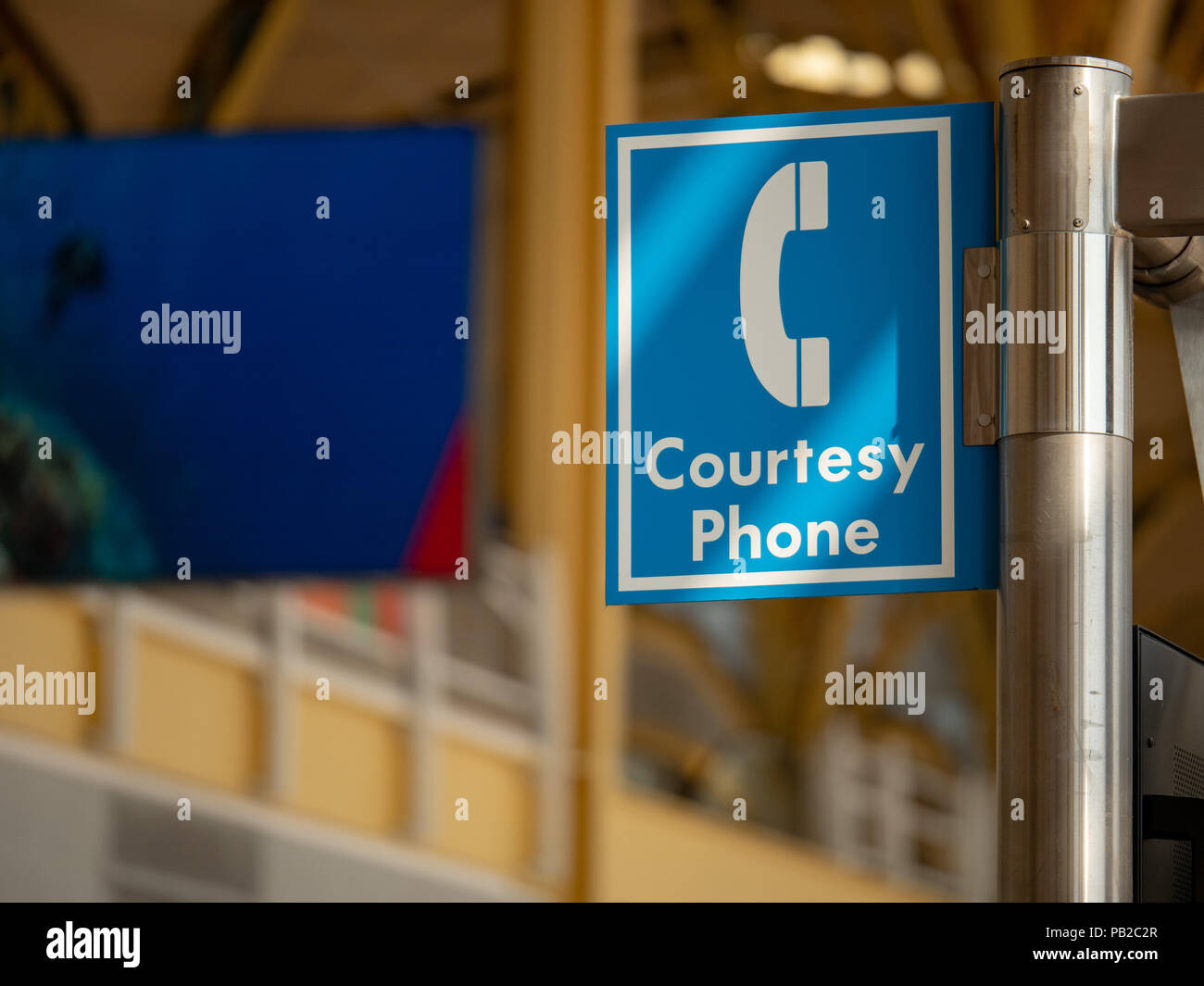 Blue courtesy phone sign hanging high at an airport Stock Photo - Alamy