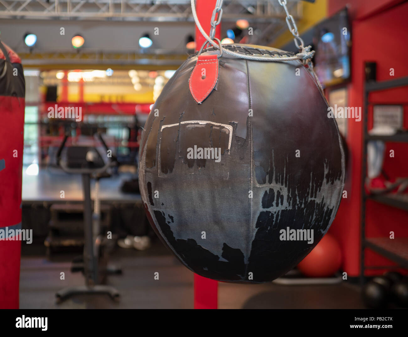 Worn, black leather wrecking ball style heavy bag hanging at a boxing ...