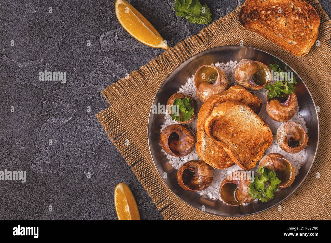 Fried snails with lemon, baguette and parsley, top view Stock Photo - Alamy