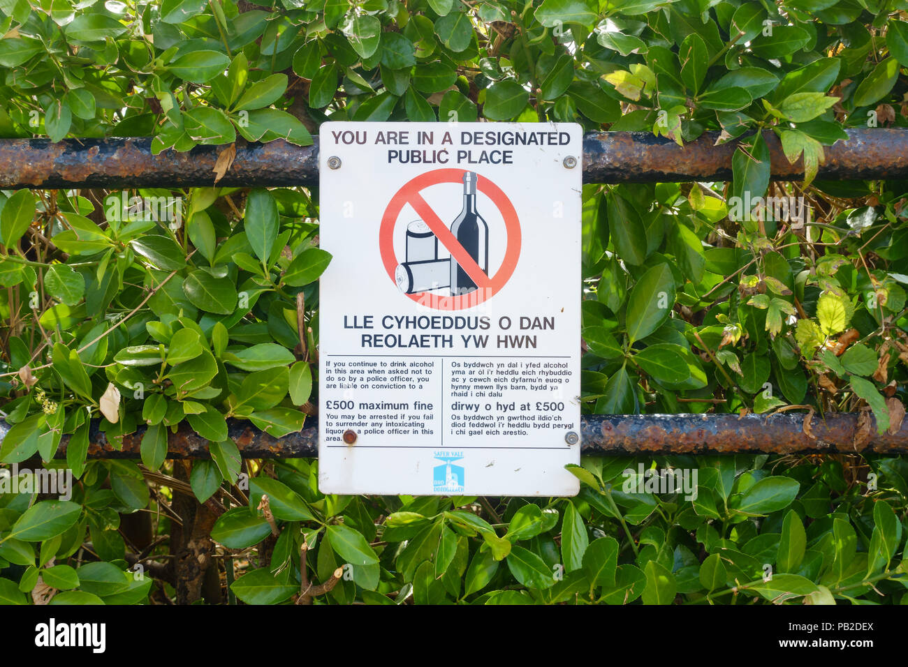 You Are In A Designated Public Place Sign in front of shrubs in a ...