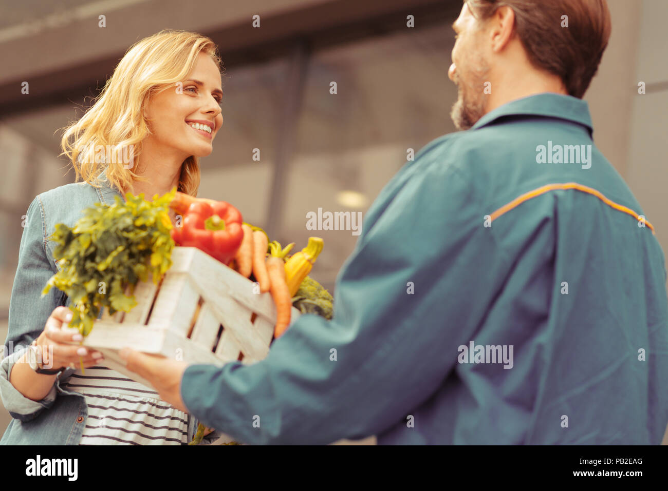 Cheerful young woman taking box with goods Stock Photo - Alamy