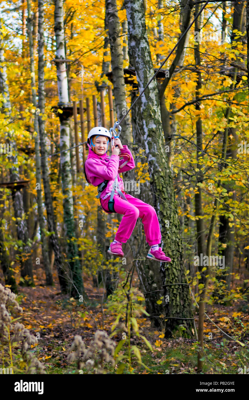 Young girl on zip line between trees in an adventure park Stock Photo ...