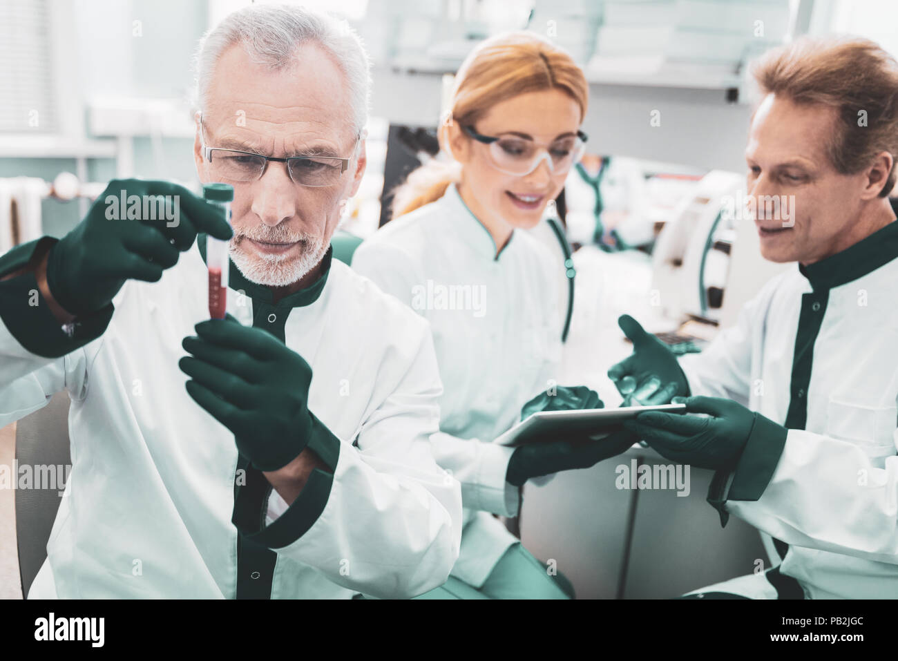 Three scientific researchers in green gloves Stock Photo - Alamy