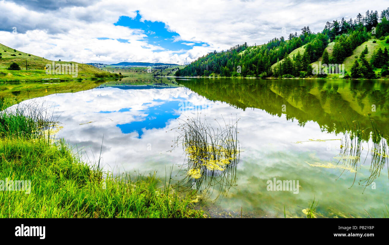 Blue Sky, Clouds and surrounding Mountains reflecting in the water of ...