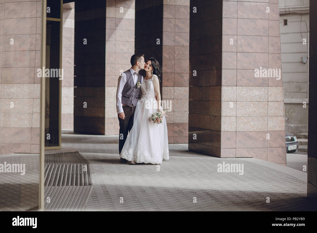 bride and groom stand near tall columns Stock Photo - Alamy
