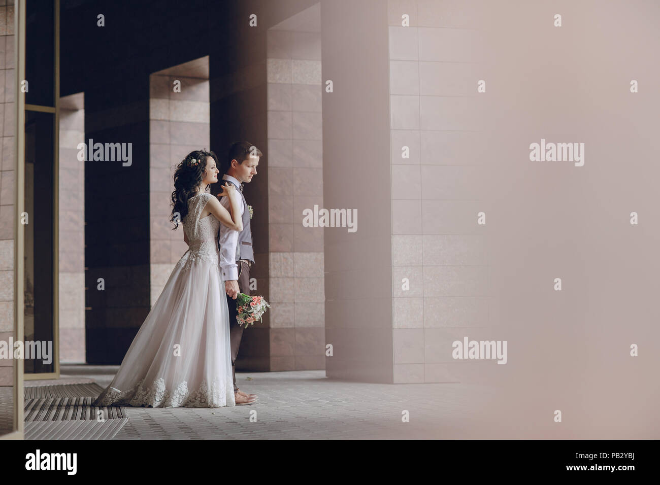 bride and groom stand near tall columns Stock Photo - Alamy