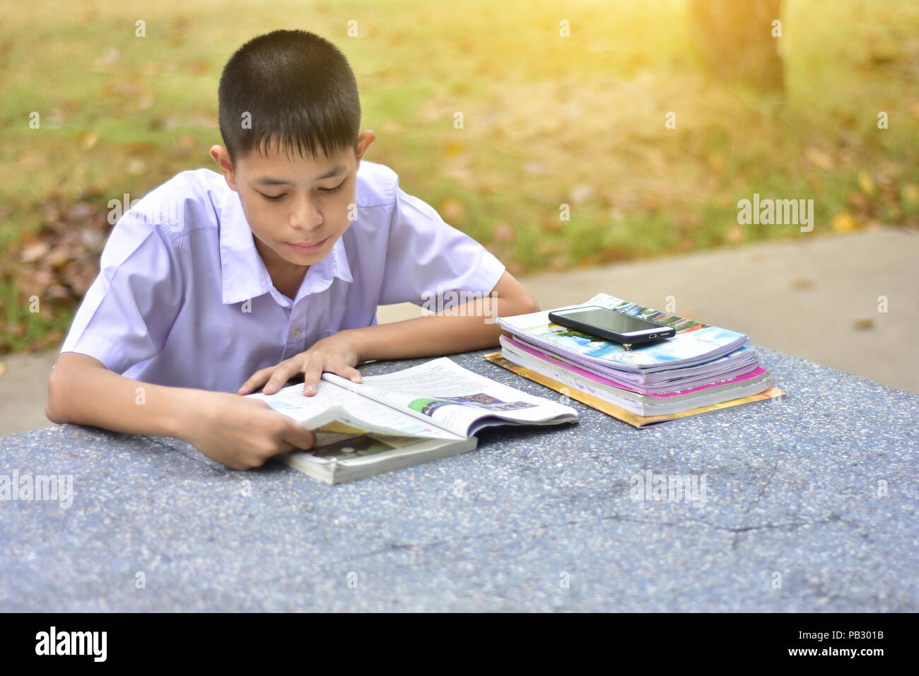 Boy reading a book at school sunlight background Stock Photo - Alamy