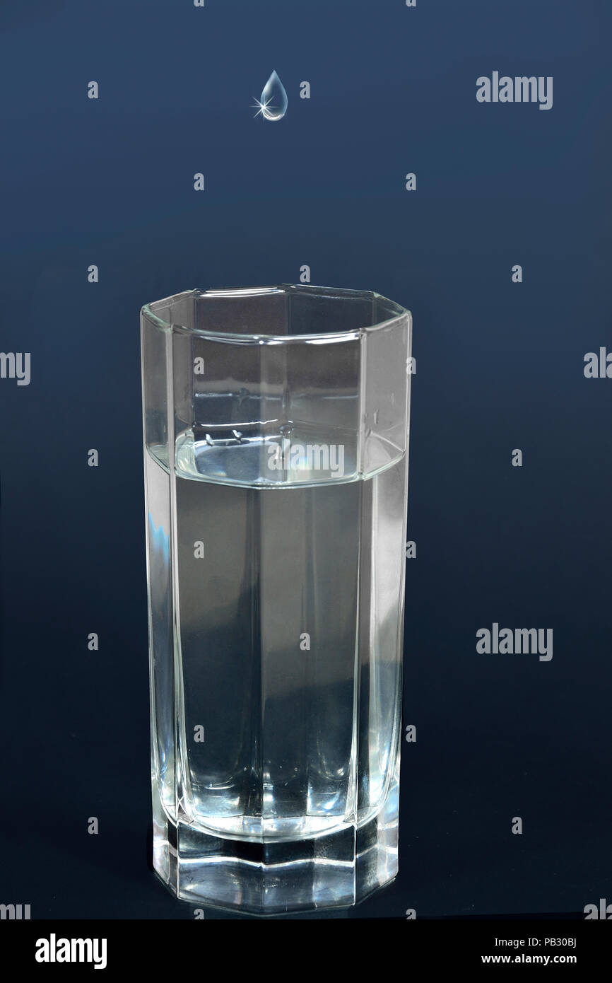 Drop of water or other liquid falling into a glass filled with a clear ...