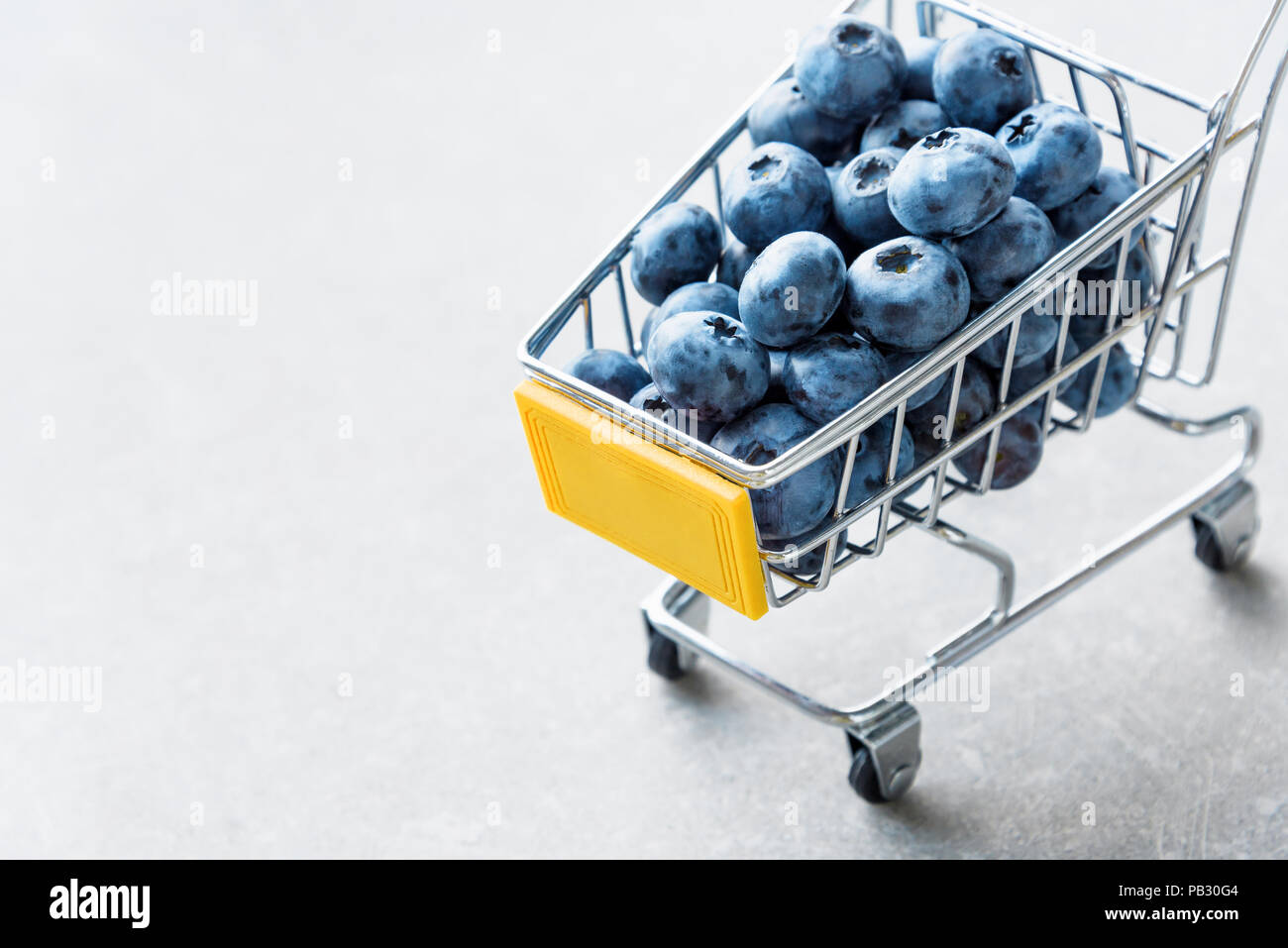 Blueberry fruits in mini shopping cart. Selective focus on the ...