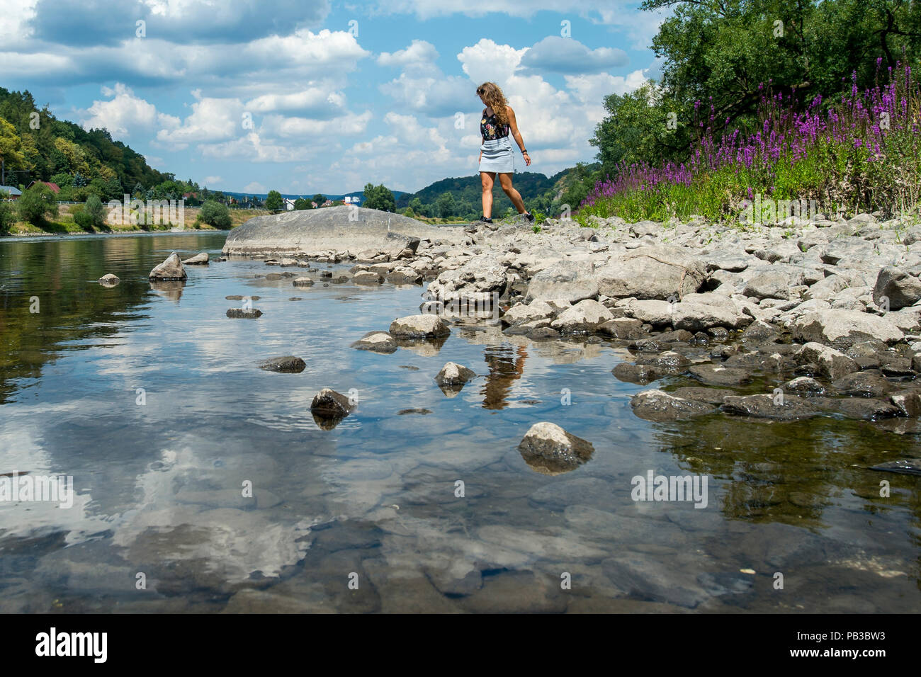 A young woman looking at a so called hunger stone in the Labe River ...