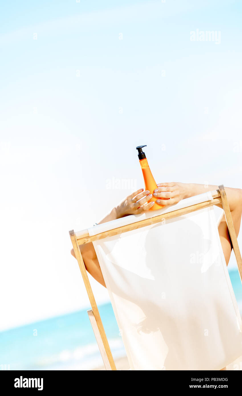 Seen from behind modern woman in swimsuit on the seashore with sun ...