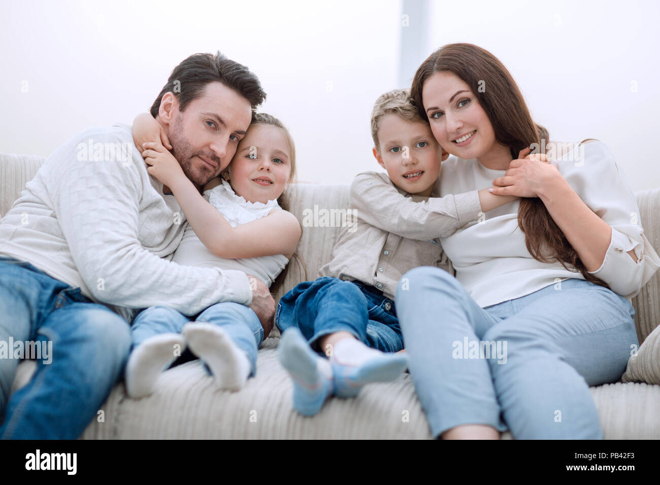 parents hug their children sitting on the couch Stock Photo - Alamy