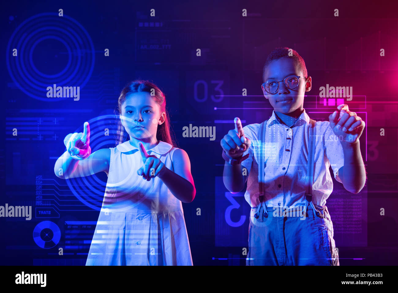 Calm kids looking concentrated while pointing to the screen Stock Photo ...