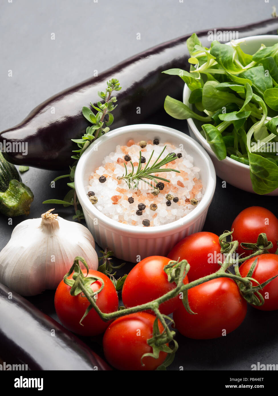 Mix of raw vegetables with salt, spices on dark background. Clean ...
