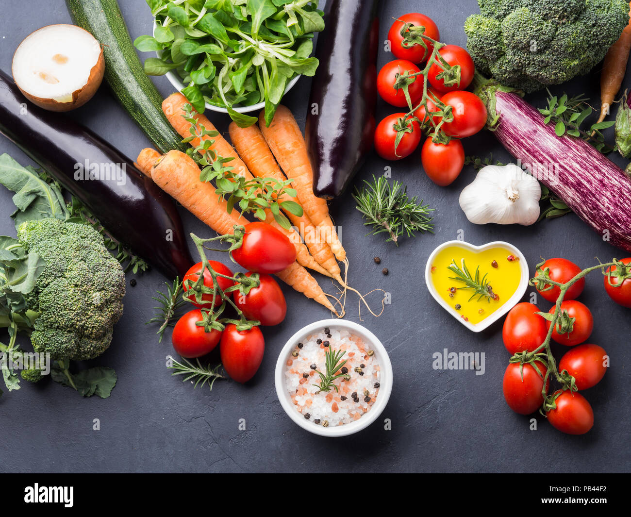 Mix of raw vegetables with salt, spices on dark background. Clean ...