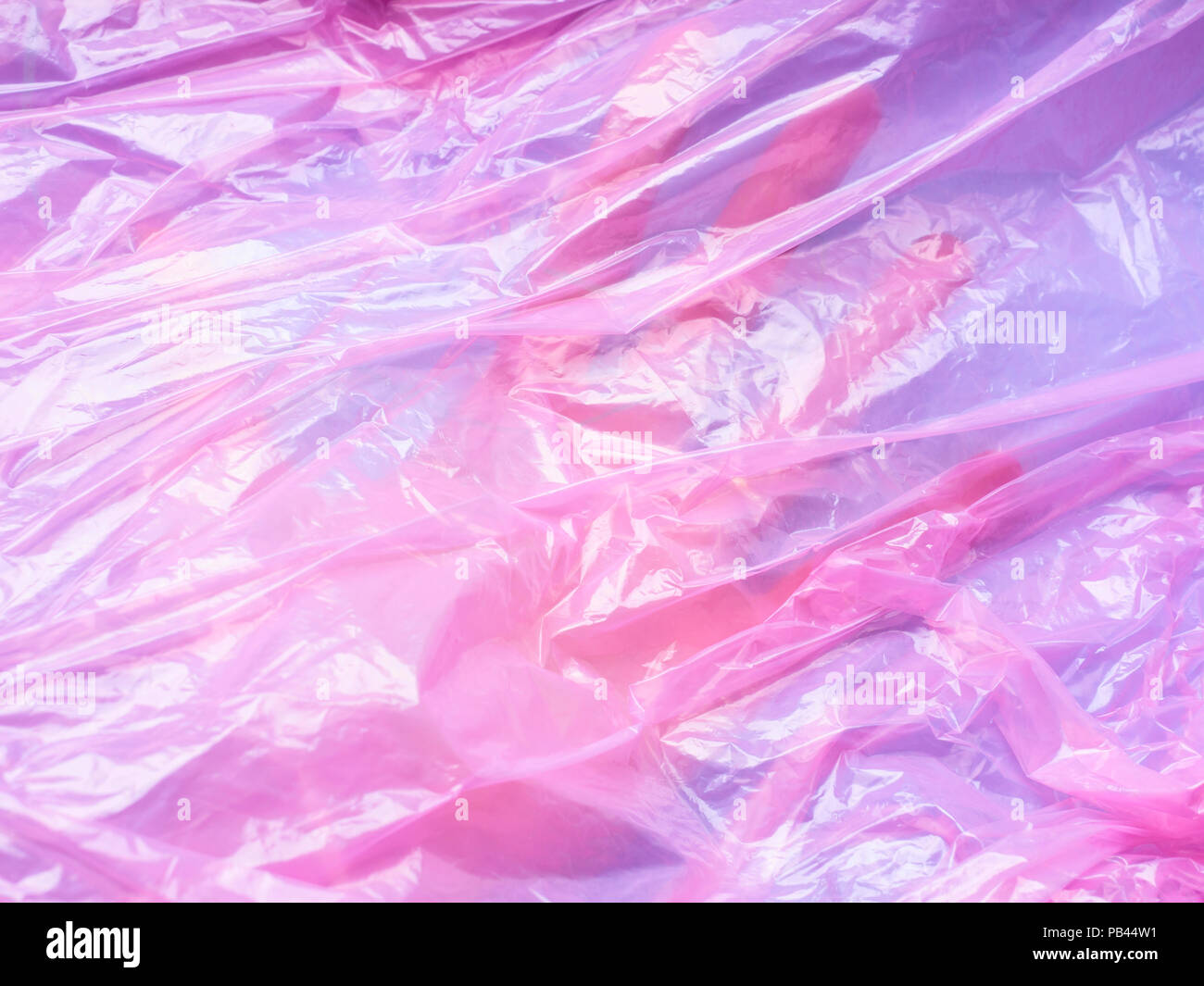 Woman's hand under pink plastic bag film. Abstract concept background ...