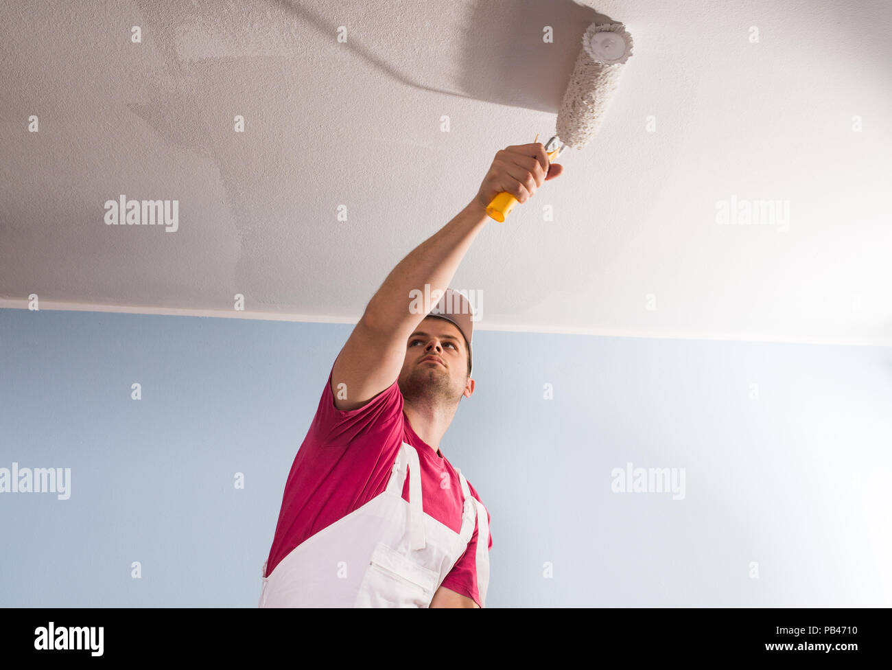 Young Painter In White Uniform Painting With Paint Roller Stock Photo ...