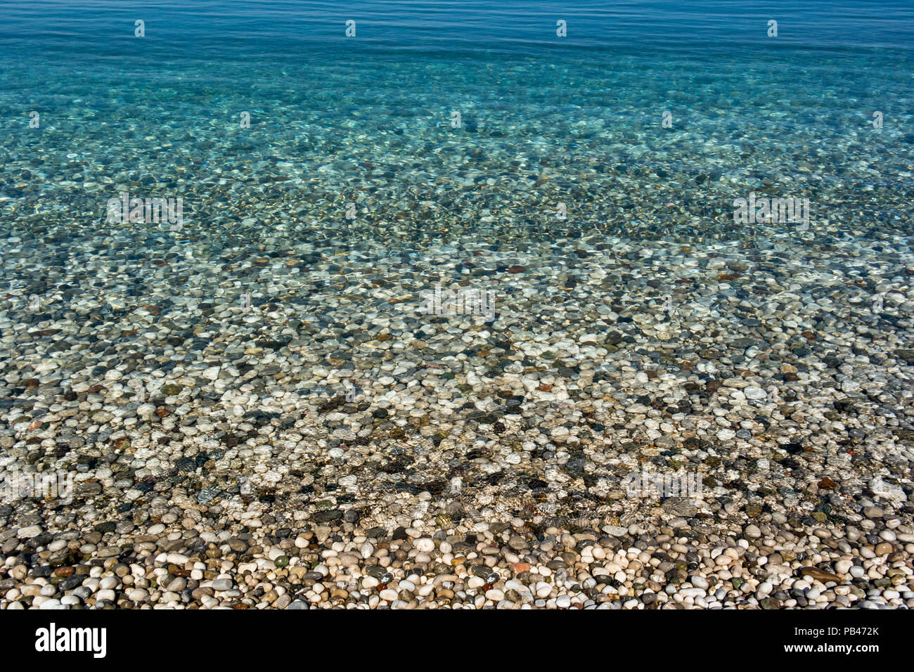 The crystal clear Mediterranean shore line sea shows up the pebble ...