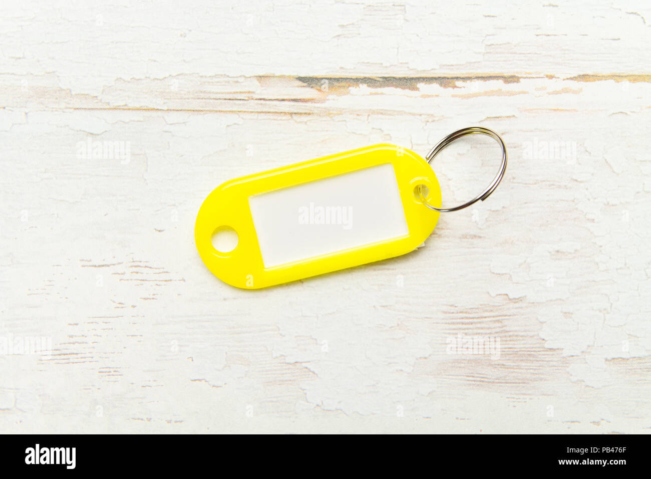 Yellow key tag on a light tree textured background.The concept of ...