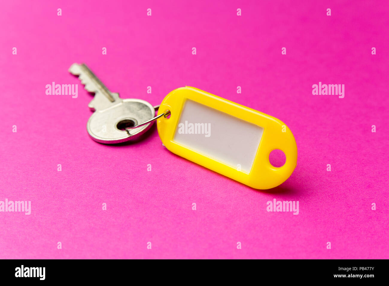 Yellow key tag on a purple textured cardboard background.The concept of ...